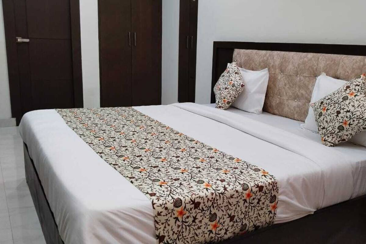 Cama bem arrumada com colcha estampada, duas almofadas e cabeceira.