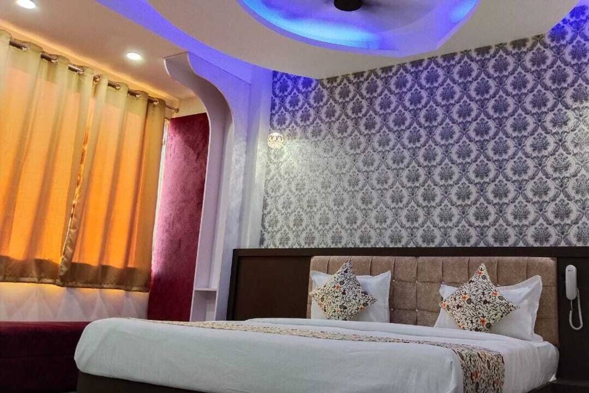 Quarto de hotel com cama, papel de parede estampado, telefone e tomada.