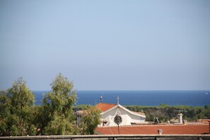 Vista costeira com um edifício de telhado vermelho e uma cruz no topo, cercado por vegetação.