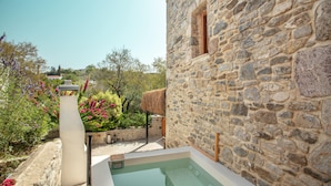 Um edifício de pedra com piscina de pedra e estrutura de telhado de palha.
