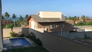 Um bairro residencial com piscina, uma casa pequena e vista para o oceano.