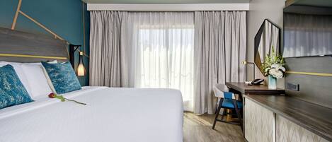 Quarto de hotel moderno com uma cama grande, uma escrivaninha e um espelho.