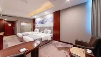 Quarto de hotel com cama, escrivaninha, cadeira e mesa pequena.