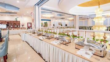 Disposição de buffet com várias estações de serviço, um candelabro e interior bem iluminado.