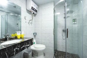 Casa de banho com lavatório de mármore, sanita e cabine de duche com parede de vidro.