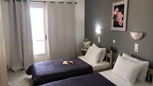 Quarto de hotel com duas camas, uma mesinha de cabeceira com abajur, iluminação embutida na parede e um quadro emoldurado.