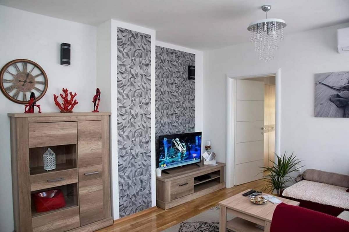 Uma sala de estar moderna com televisão de tela plana, um armário de madeira e um candelabro.