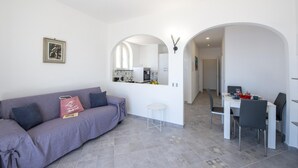 Uma sala de estar moderna com um sofá, uma mesinha e um espaço de refeições com cadeiras e uma mesa.