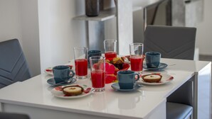 Mesa de café da manhã com várias xícaras e pratos, alguns com comida e bebida.