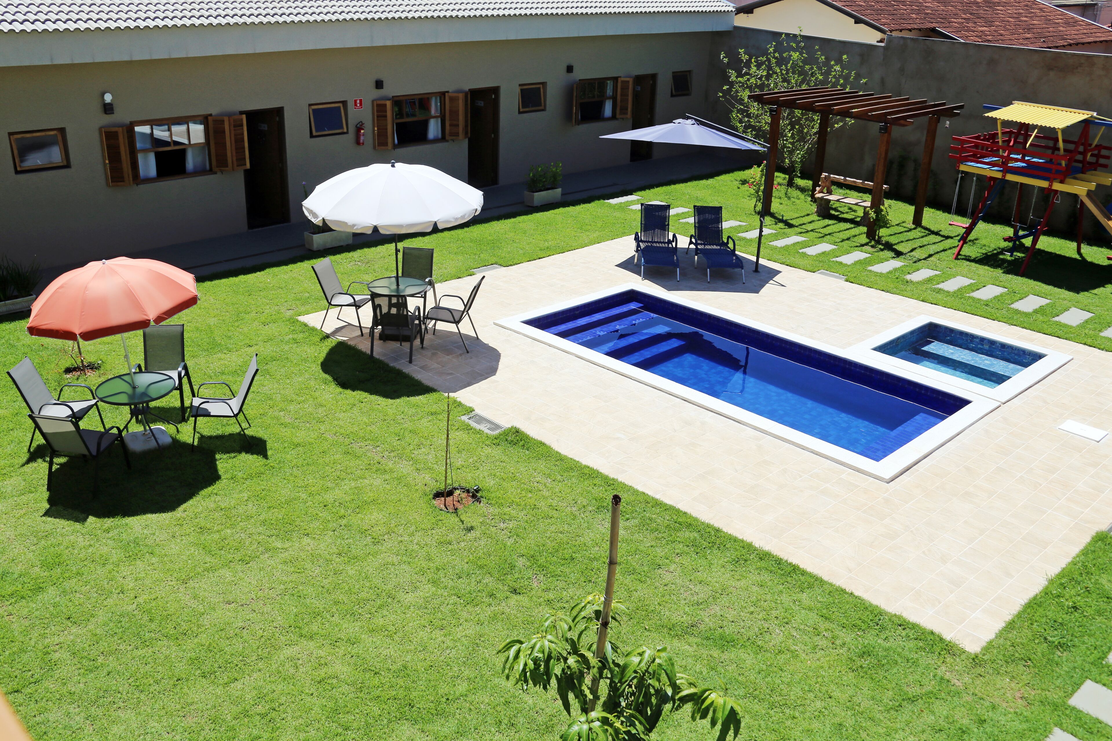 Um quintal com piscina, móveis de pátio e área de estar coberta.