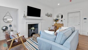 Uma sala de estar moderna com lareira, TV de tela plana, sofá e mesa de centro.