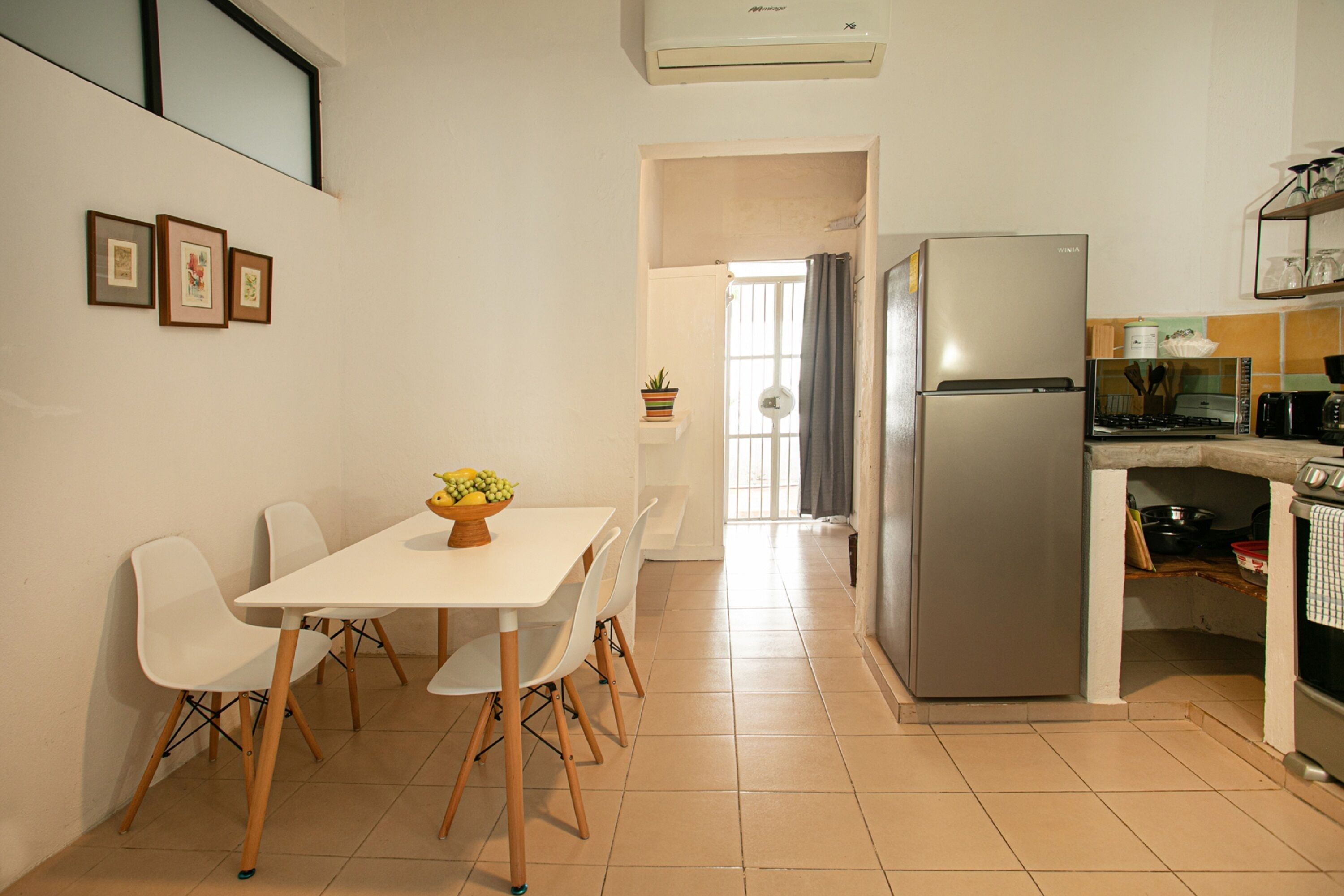 Cozinha moderna com frigorífico, micro-ondas e fogão. Existe uma área de refeições com mesa e cadeiras.