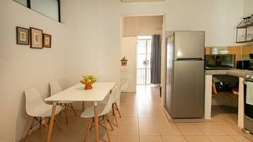 Cozinha moderna com frigorífico, micro-ondas e fogão. Existe uma área de refeições com mesa e cadeiras.