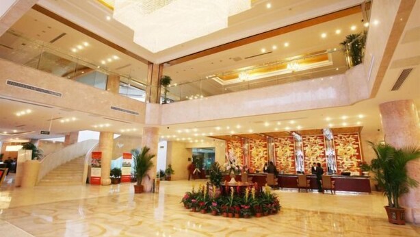 Um hall amplo com balcão de recepção, escadaria e uma fonte decorativa.