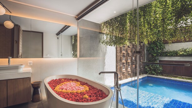 Uma casa de banho moderna com uma banheira independente cheia de pedrinhas coloridas, uma piscina envidraçada e um lavatório de madeira.