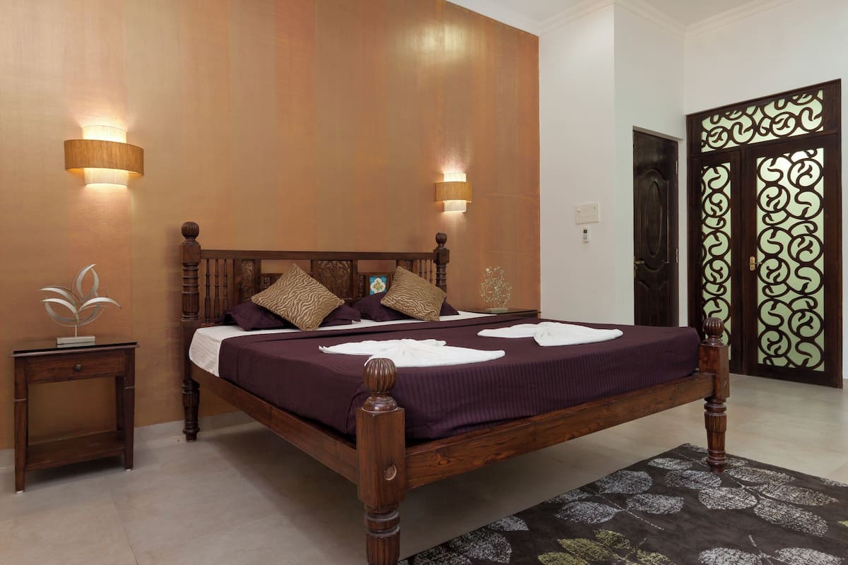Uma cama de madeira com cabeceira, duas mesas de cabeceira e um painel decorativo na parede.