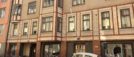 Carro antigo estacionado em frente a um edifício com várias janelas e uma porta.