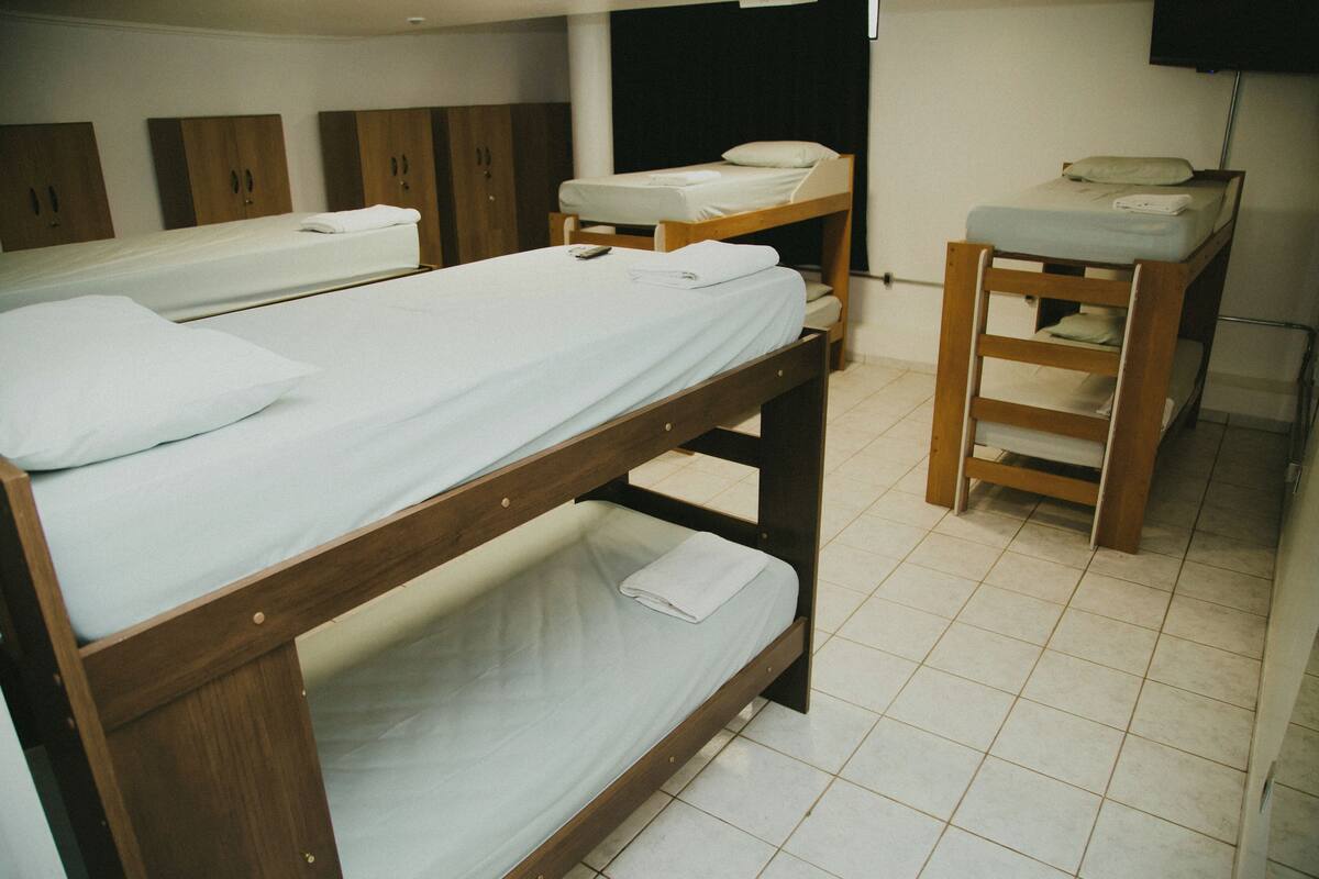 Um quarto em dormitório com beliches, mobiliário de madeira e uma televisão na parede.
