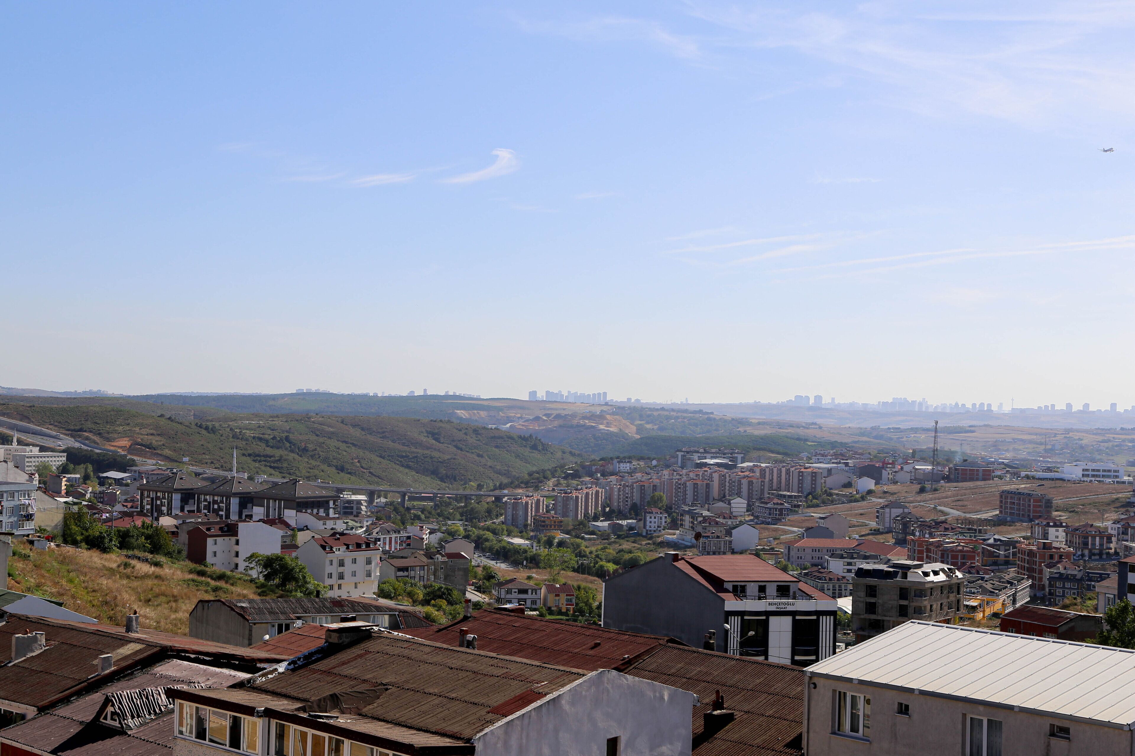 Paisagem urbana com diversos edifícios, incluindo construções residenciais e comerciais, e uma vista distante do horizonte da cidade.