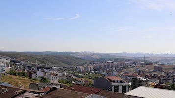 Paisagem urbana com diversos edifícios, incluindo construções residenciais e comerciais, e uma vista distante do horizonte da cidade.