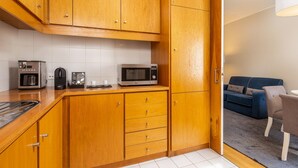 Uma cozinha compacta com armários de madeira, micro-ondas, cafeteira e torradeira.