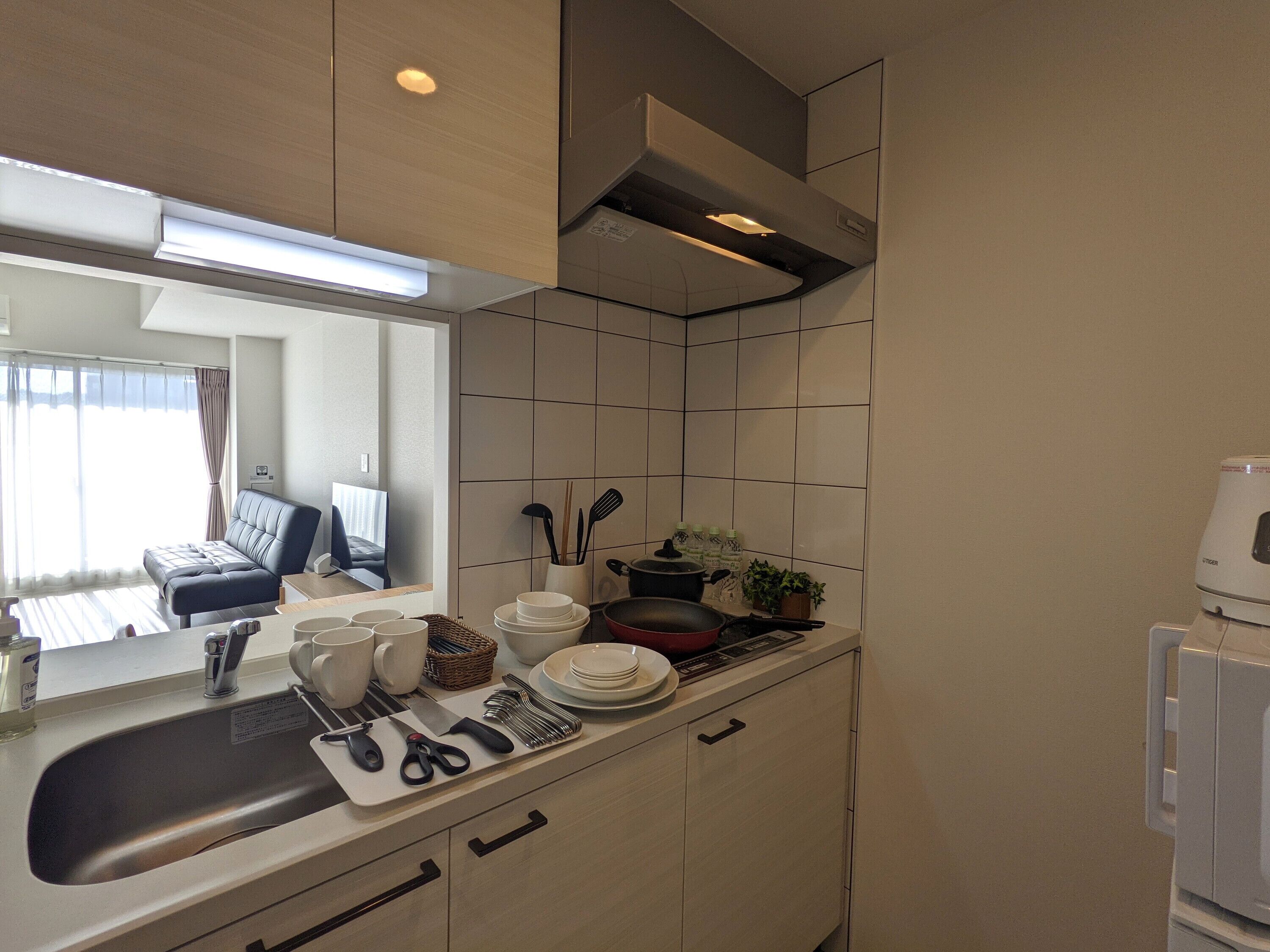 Uma cozinha moderna com forno embutido, pia e área de jantar com sofá e mesa.