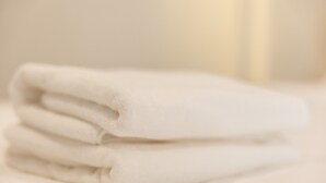 Uma pilha de toalhas brancas sobre a cama.