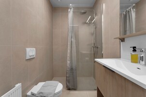 Uma casa de banho moderna com chuveiro, sanita e lavatório.