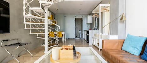 Uma sala de estar moderna com uma escada em espiral, uma mesa de centro de vidro, um sofá de couro e um lustre.