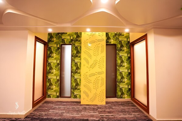 Um corredor com design moderno, apresentando uma parede texturizada com padrão de folhagem e um painel central amarelo.