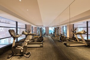 Uma academia moderna com diversos equipamentos de cardio, amplas janelas e um layout espaçoso.