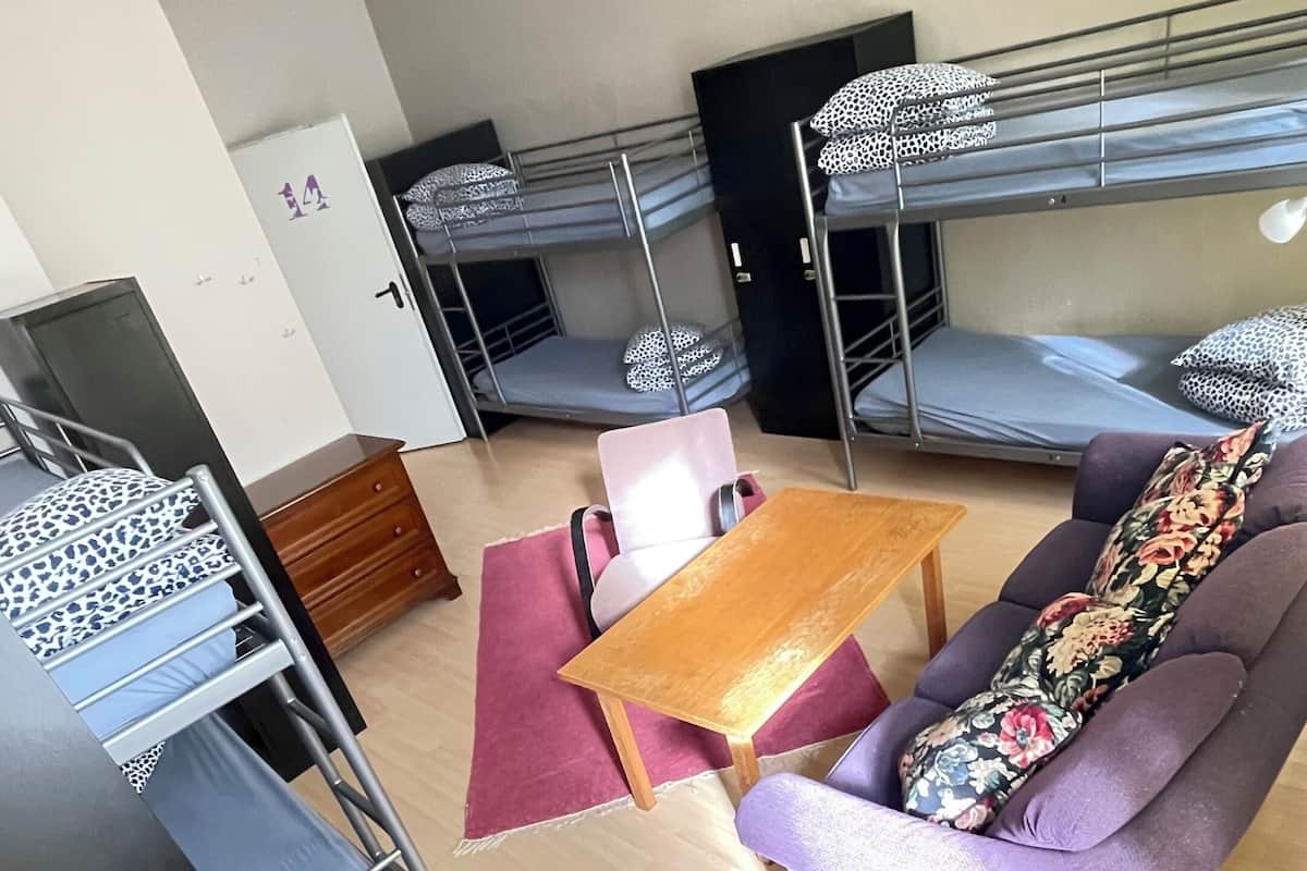 Quarto em dormitório com beliches, sofá, mesa de madeira e uma cadeira.