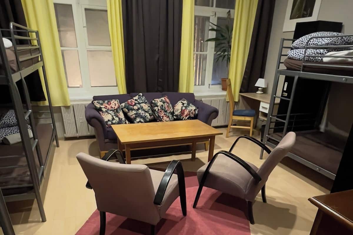 Um quarto com beliche, sofá, mesa de jantar e duas cadeiras.