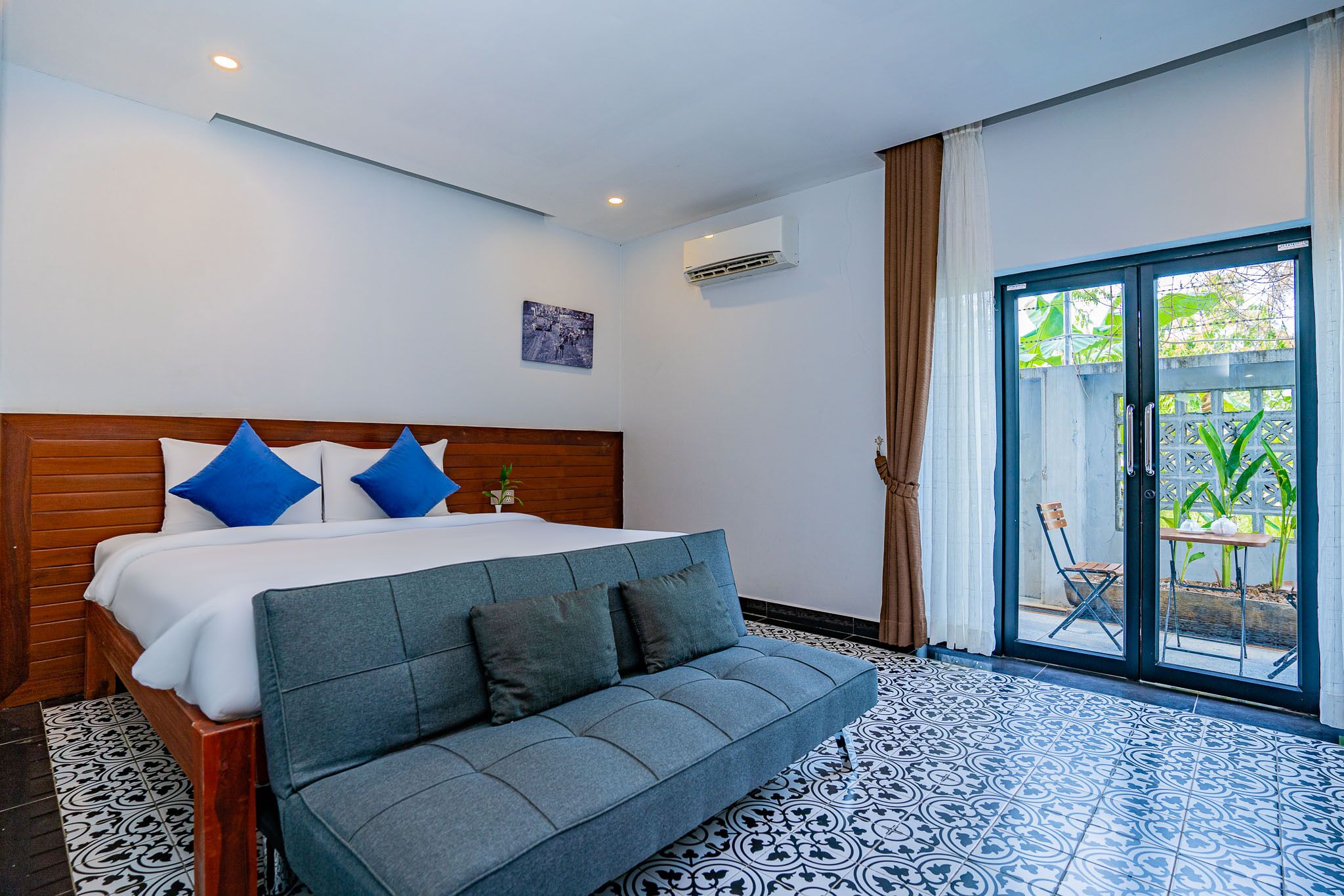Quarto com cama, sofá, janela com cortinas e chão em mosaico.