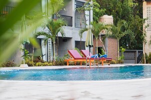 Área da piscina com duas espreguiçadeiras, um reservatório de água e vegetação ao redor.