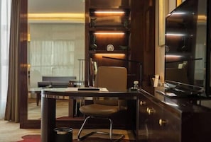 Quarto de hotel moderno com escrivaninha, cadeira e um espelho grande.
