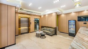 Um lobby moderno com um sofá, uma mesa de centro e um frigorífico.