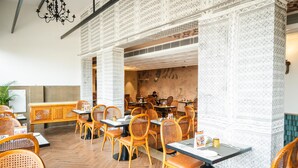 Restaurante com móveis de madeira, paredes estampadas e um candelabro.