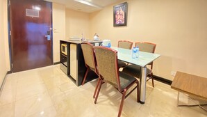 Uma sala de jantar com uma mesa, cadeiras, bancada de cozinha e uma porta.