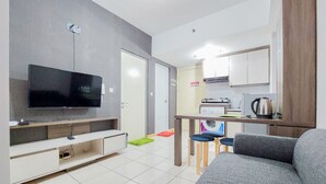 Uma sala de estar moderna com televisão de tela plana, sofá cinza e uma área de jantar com cadeiras e mesa.