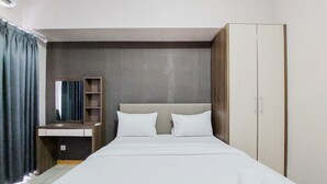 Quarto de hotel com cama, guarda-roupa, escrivaninha com espelho e cortina.