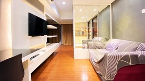 Uma sala de estar moderna com televisão de tela plana na parede, um sofá e piso de madeira.