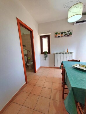 Uma área de refeições com mesa posta para dois, uma janela com vista e um radiador na parede.