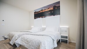 Quarto com duas camas, uma mesinha de cabeceira e um quadro pendurado na parede.