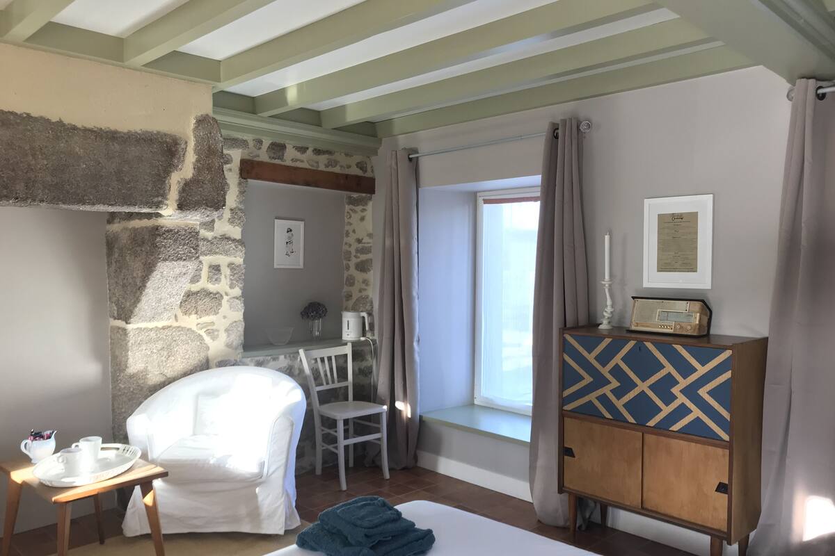 Um quarto acolhedor com uma cama, uma cadeira, uma escrivaninha e um armário.