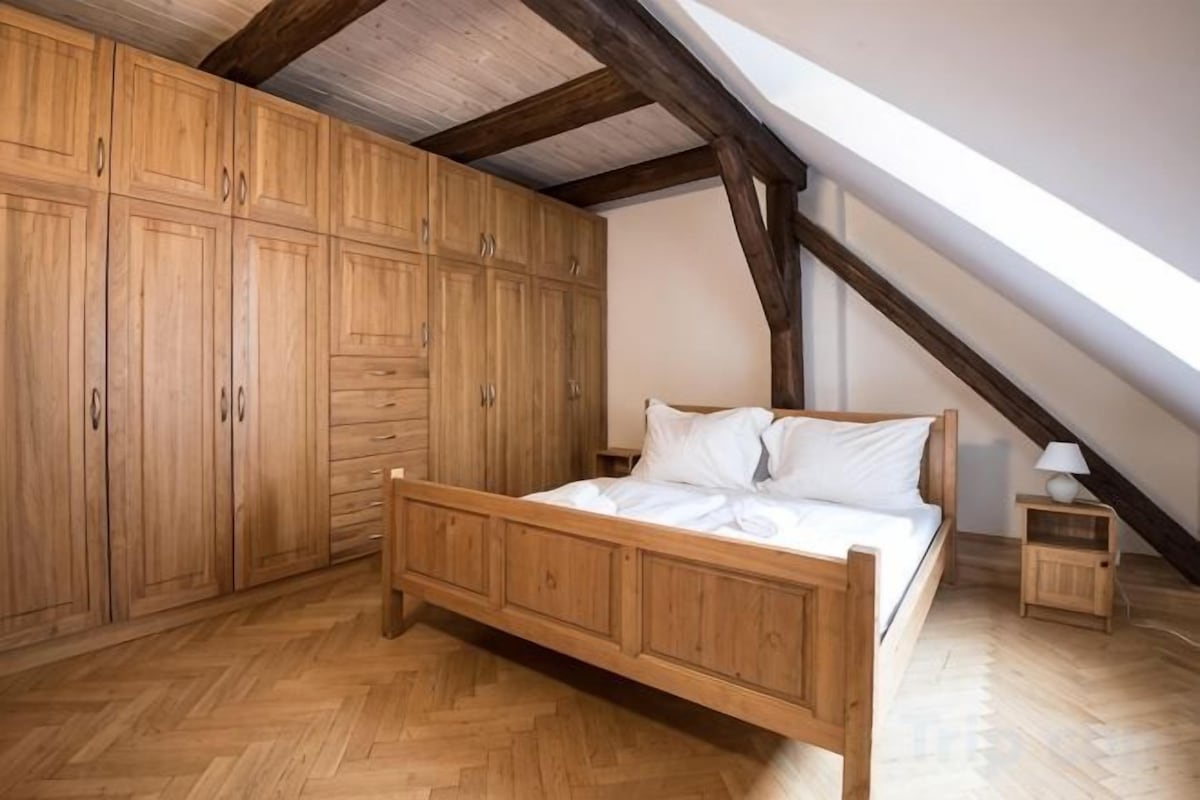Quarto com cama de madeira, guarda-roupa e mesa de cabeceira.