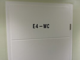 Uma porta branca com a etiqueta "E4-WC", indicando um espaço ou área.