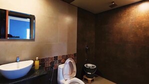 Casa de banho moderna com uma sanita branca, uma sanita e uma área de duche.