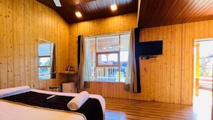 Um quarto com painéis de madeira, uma cama, uma mesinha e uma janela.