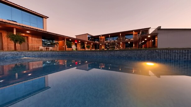 Piscina com borda azulejada, rodeada por edifícios com vários andares e varandas.